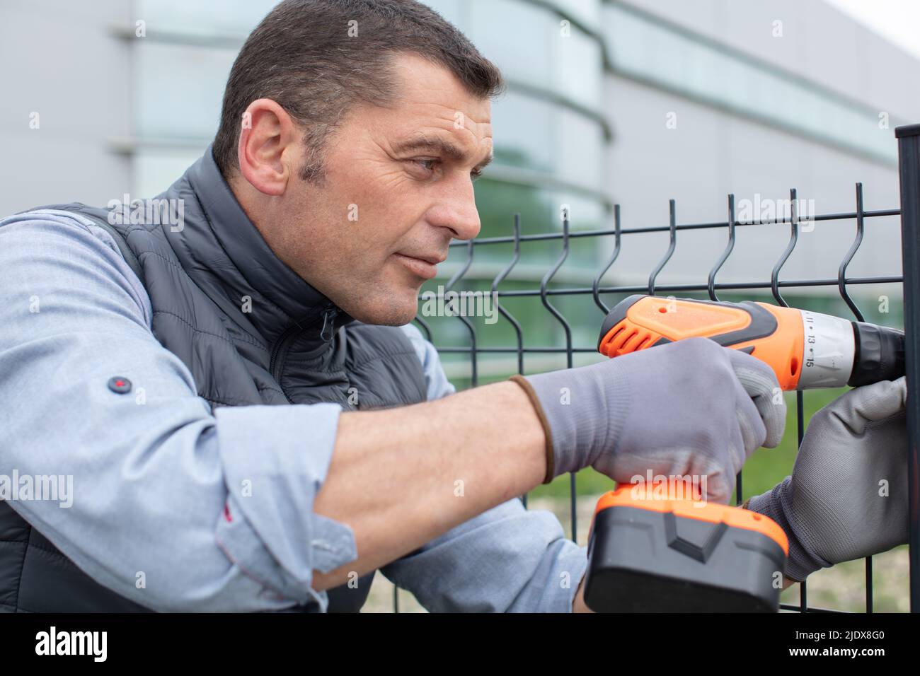 a man drill metal fence Stock Photo - Alamy
