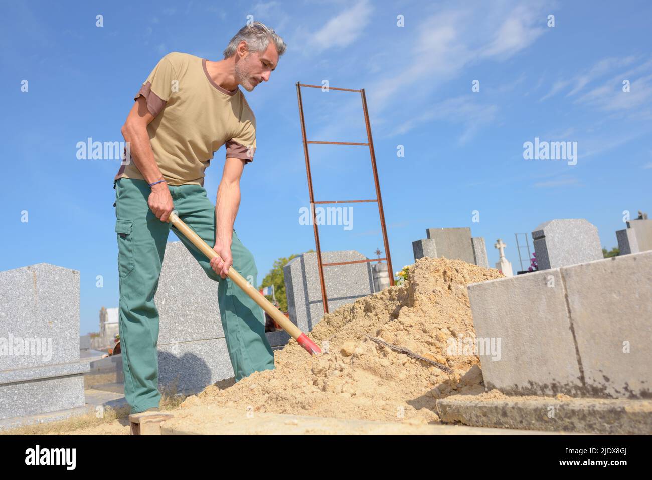Man shovelling sand in cemetery Stock Photo - Alamy