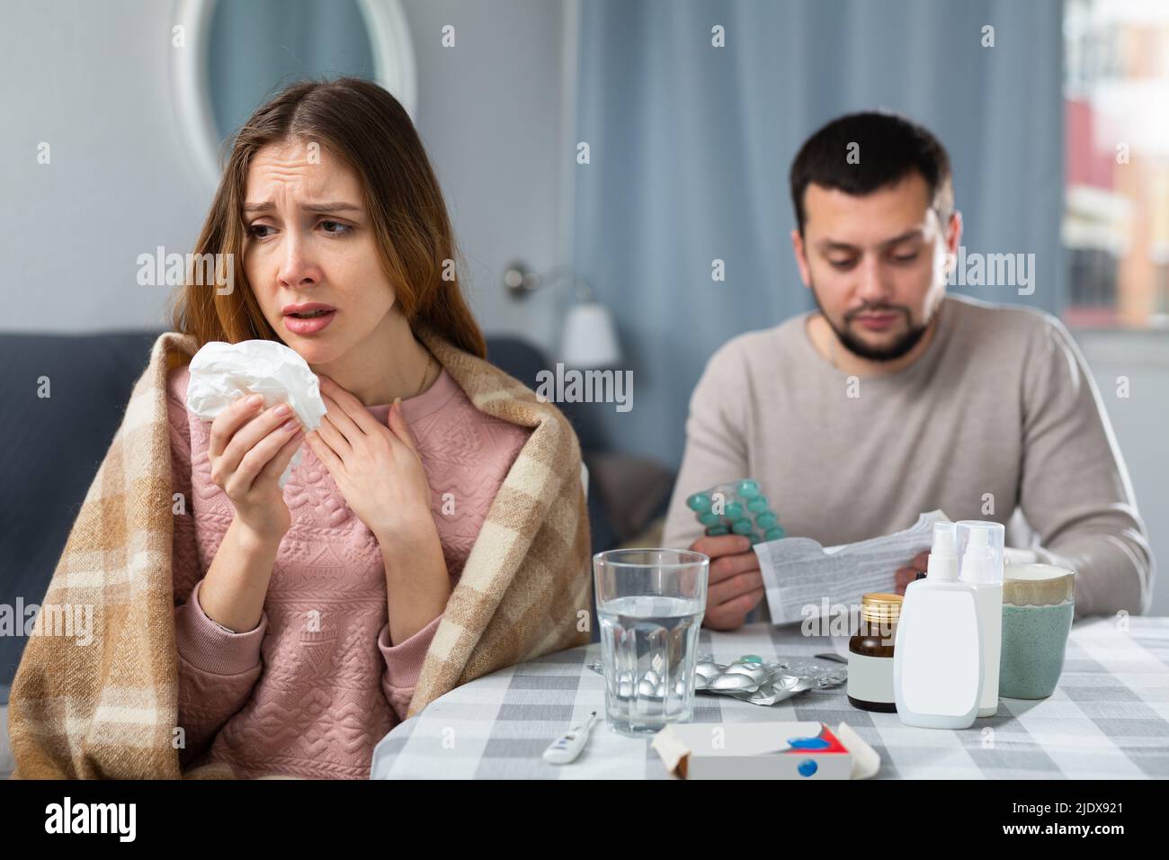Ill woman sitting at table near his husband who helping her with ...