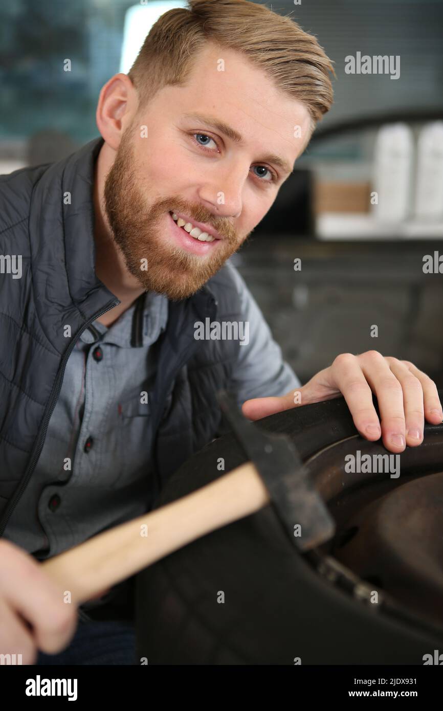 male fitter using a hammer on a car wheel Stock Photo - Alamy