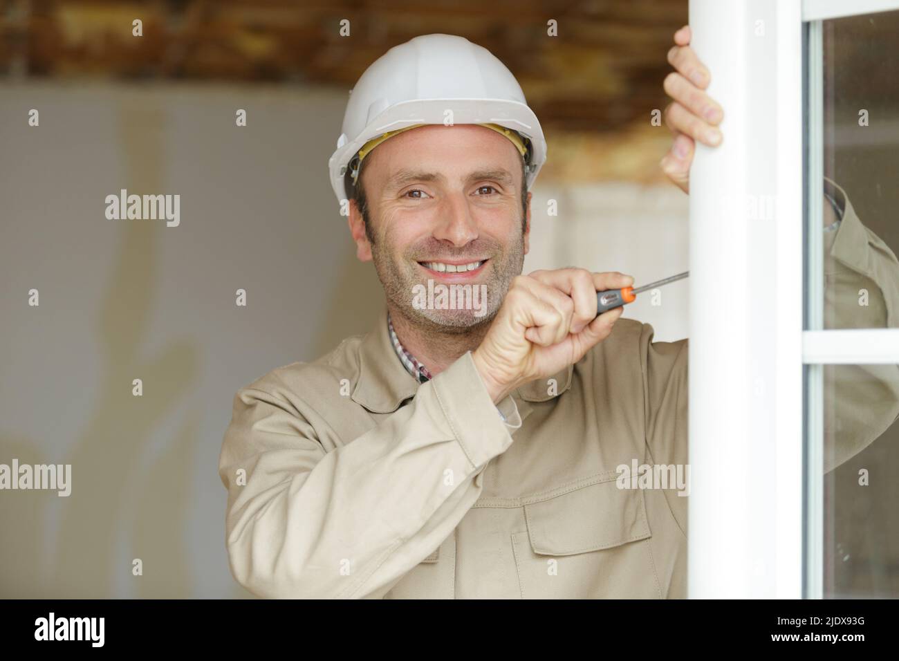 service man installing window with screwdriver Stock Photo - Alamy