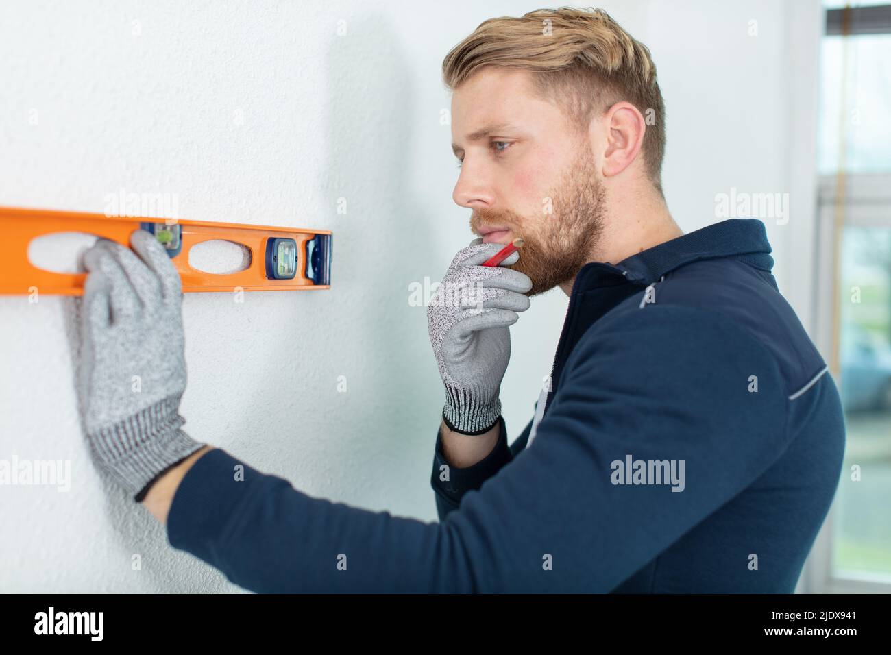 young builder checking wall with spirit level Stock Photo - Alamy