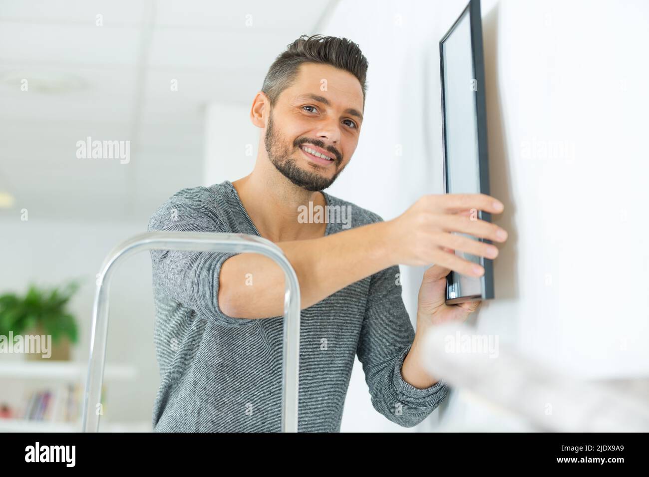 man hanging blank picture frame on wall Stock Photo - Alamy