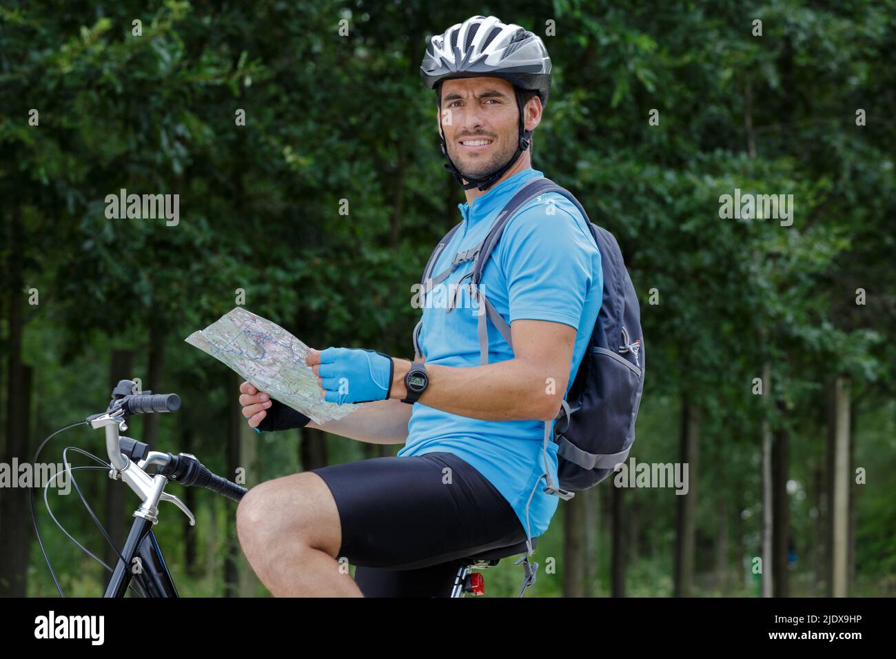 cyclist man checking map and looking around Stock Photo - Alamy