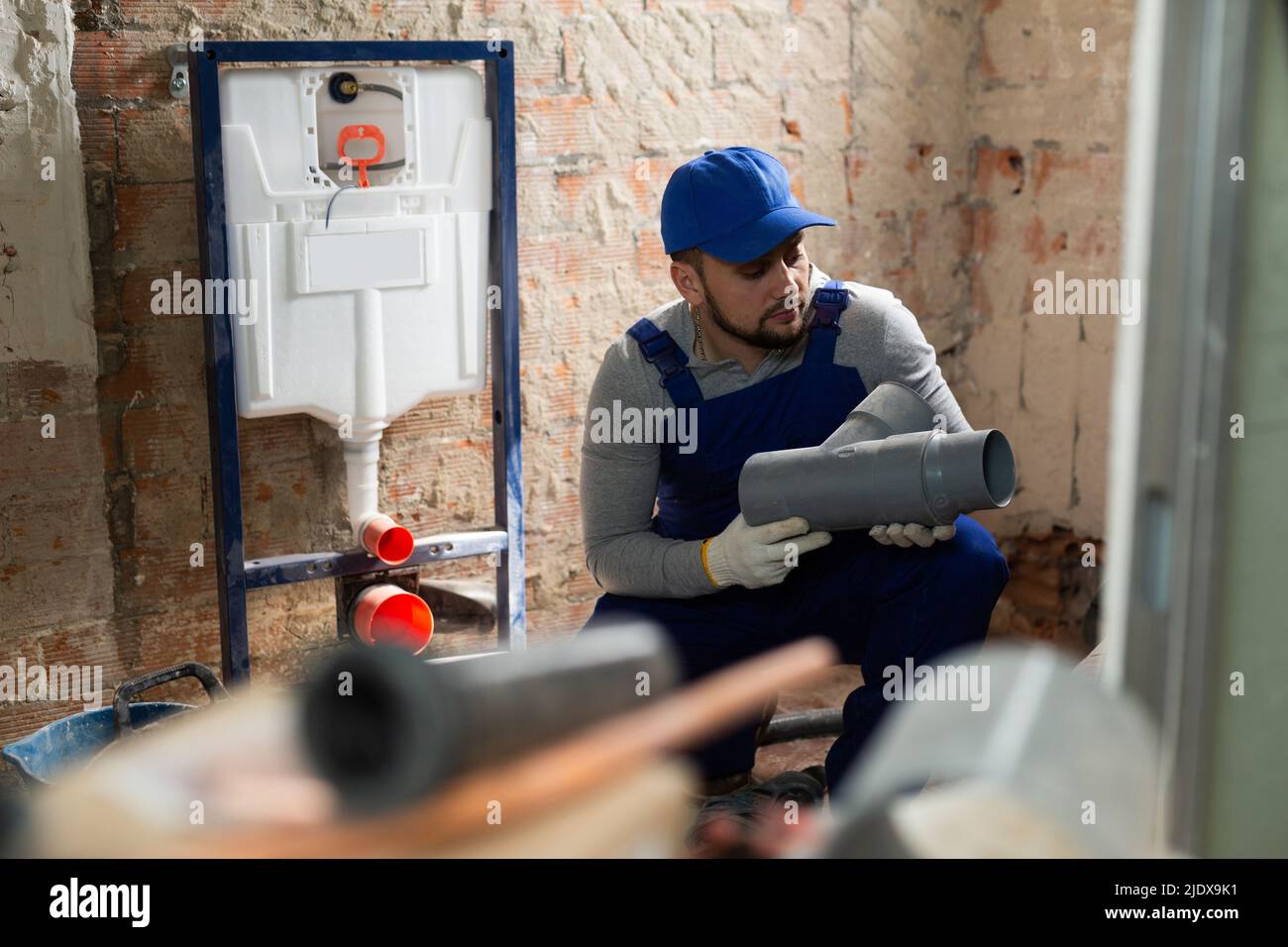 Plumber installing back to wall toilet system Stock Photo - Alamy