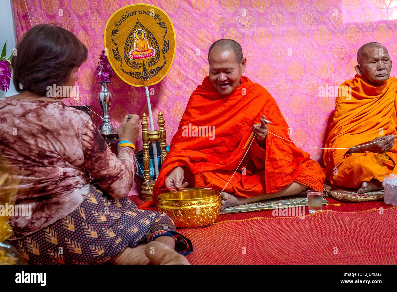 A buddhist monk smiles as he works a string ceremony with other monks ...