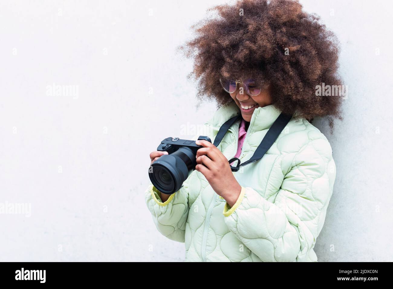 Girl with curly hair using camera in front of white wall Stock Photo ...