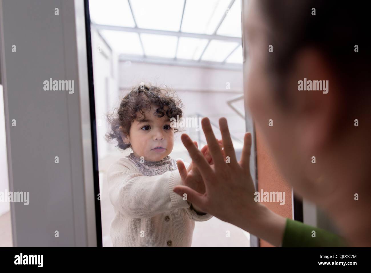 Mother and daughter touching hands separated through window pane Stock ...