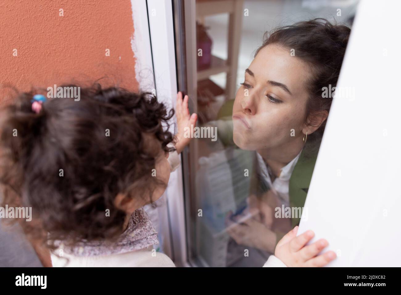 Mother and daughter kissing through window pane Stock Photo - Alamy