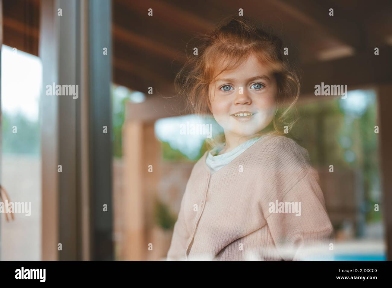 Smiling cute girl at home seen through window glass Stock Photo - Alamy