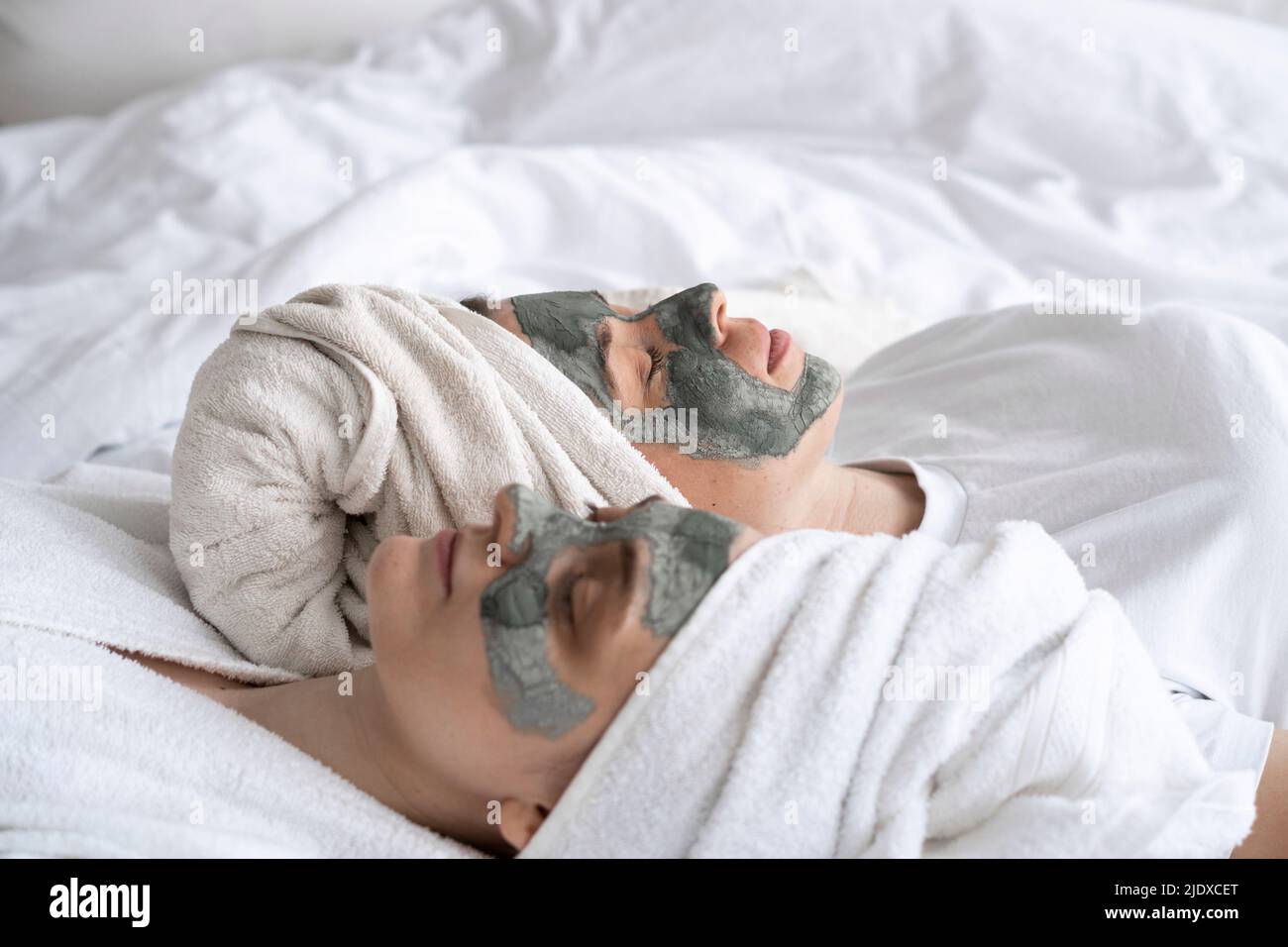 Friends wearing facial masks lying on bed at home Stock Photo - Alamy