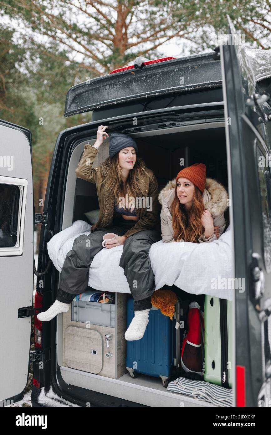 Woman talking with friend lying in campervan Stock Photo - Alamy
