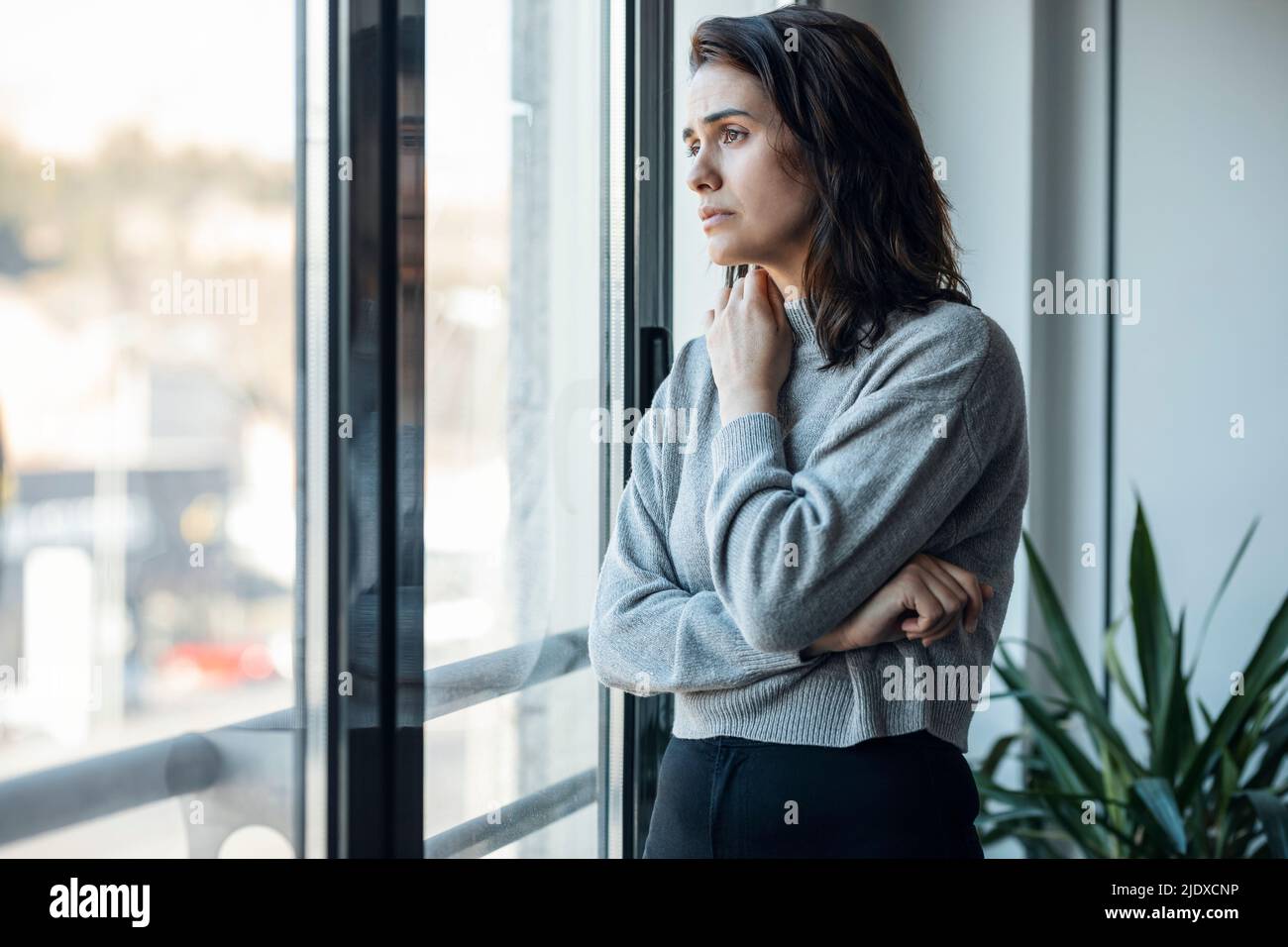 Thoughtful sad woman looking through window at home Stock Photo - Alamy