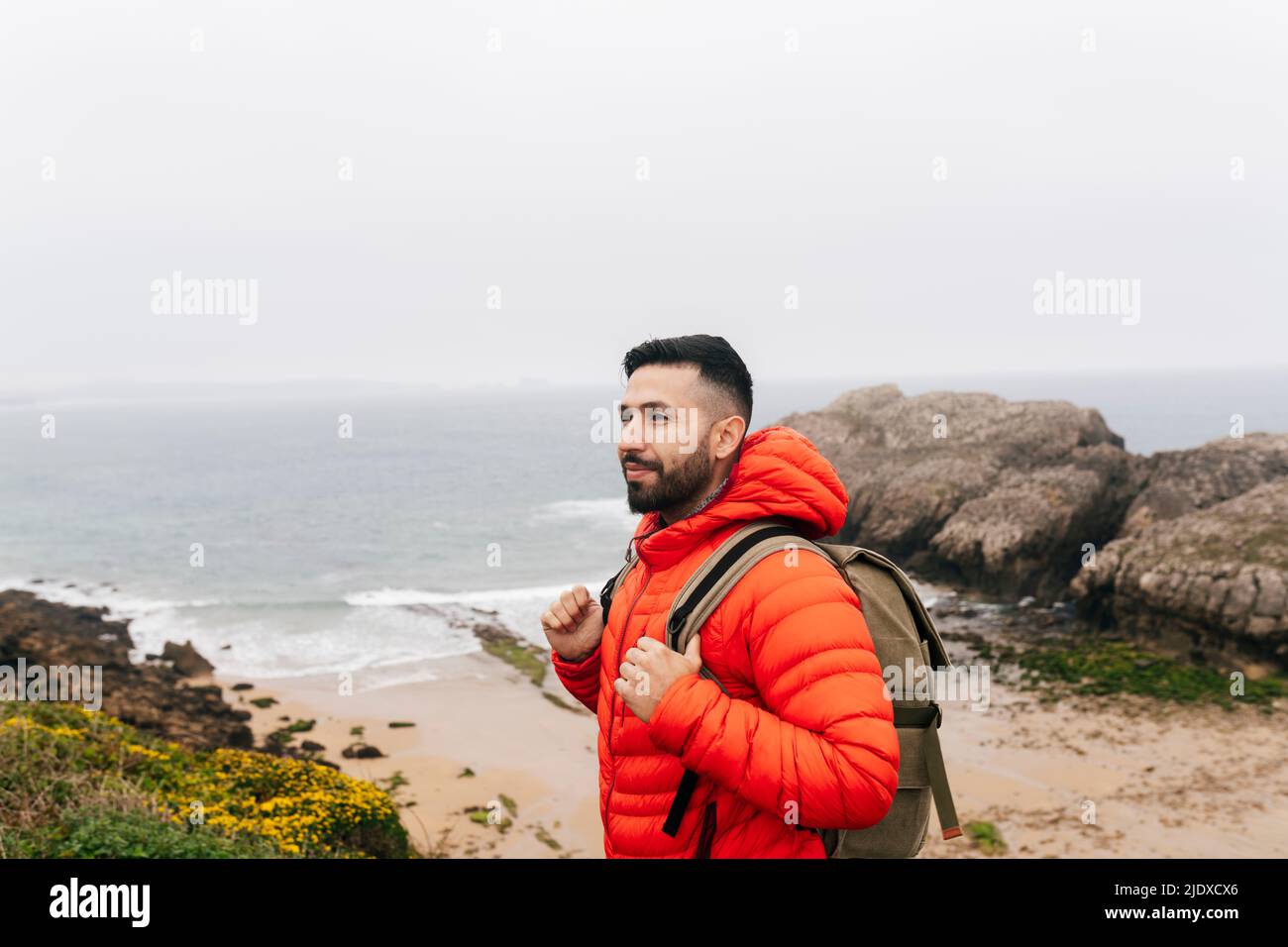 Man wearing backpack standing in front of sea Stock Photo - Alamy