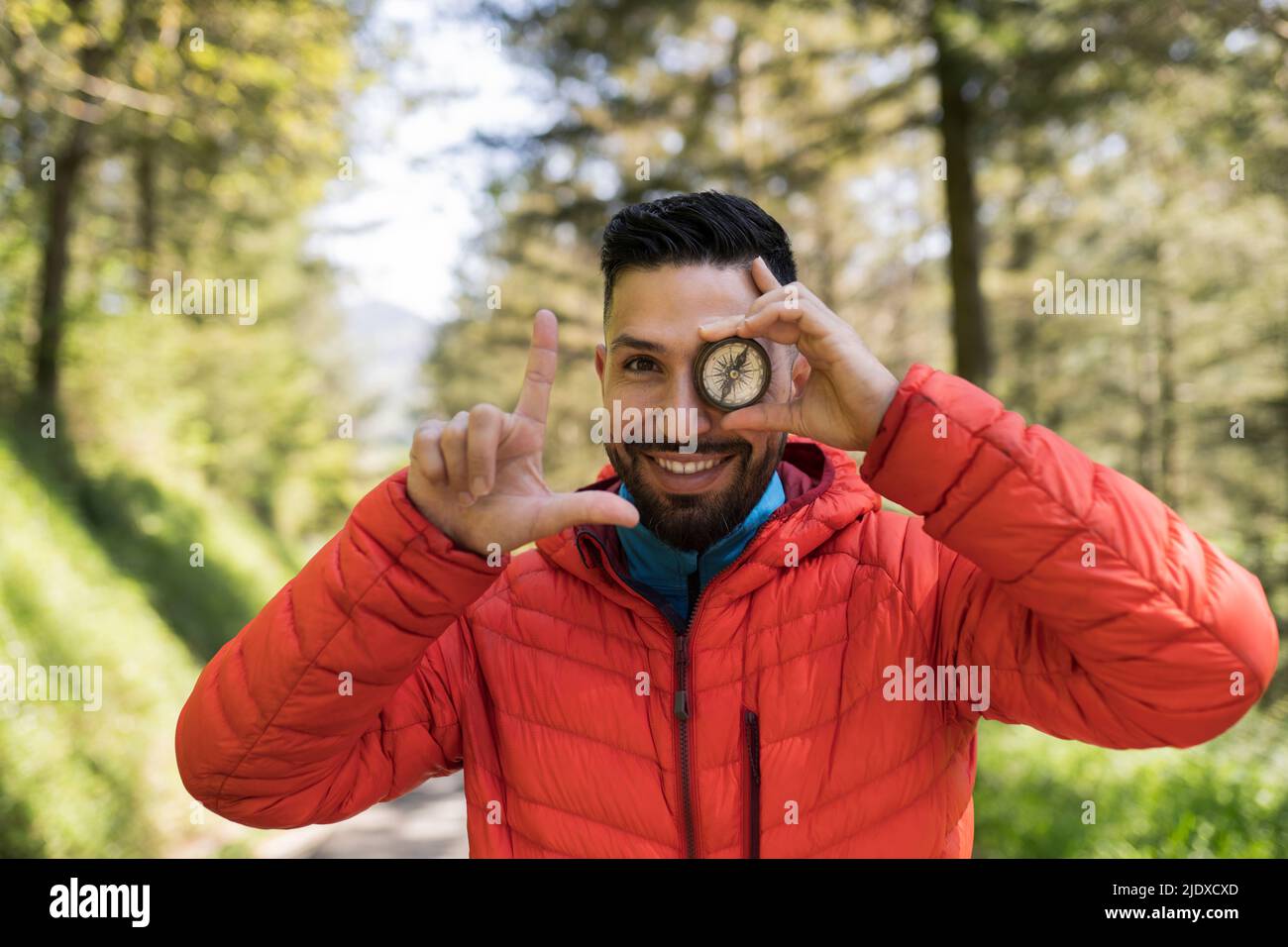 Happy man covering eye with navigational compass Stock Photo - Alamy