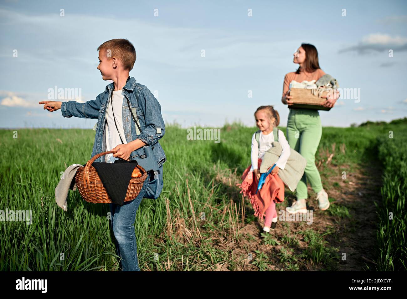 Boy with basket pointing and walking with family in field Stock Photo ...