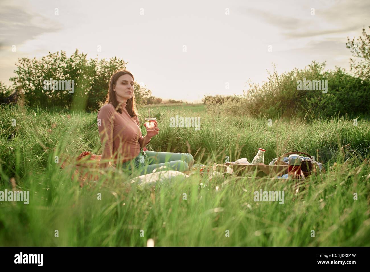 Thoughtful woman having infused water in field on weekend Stock Photo ...