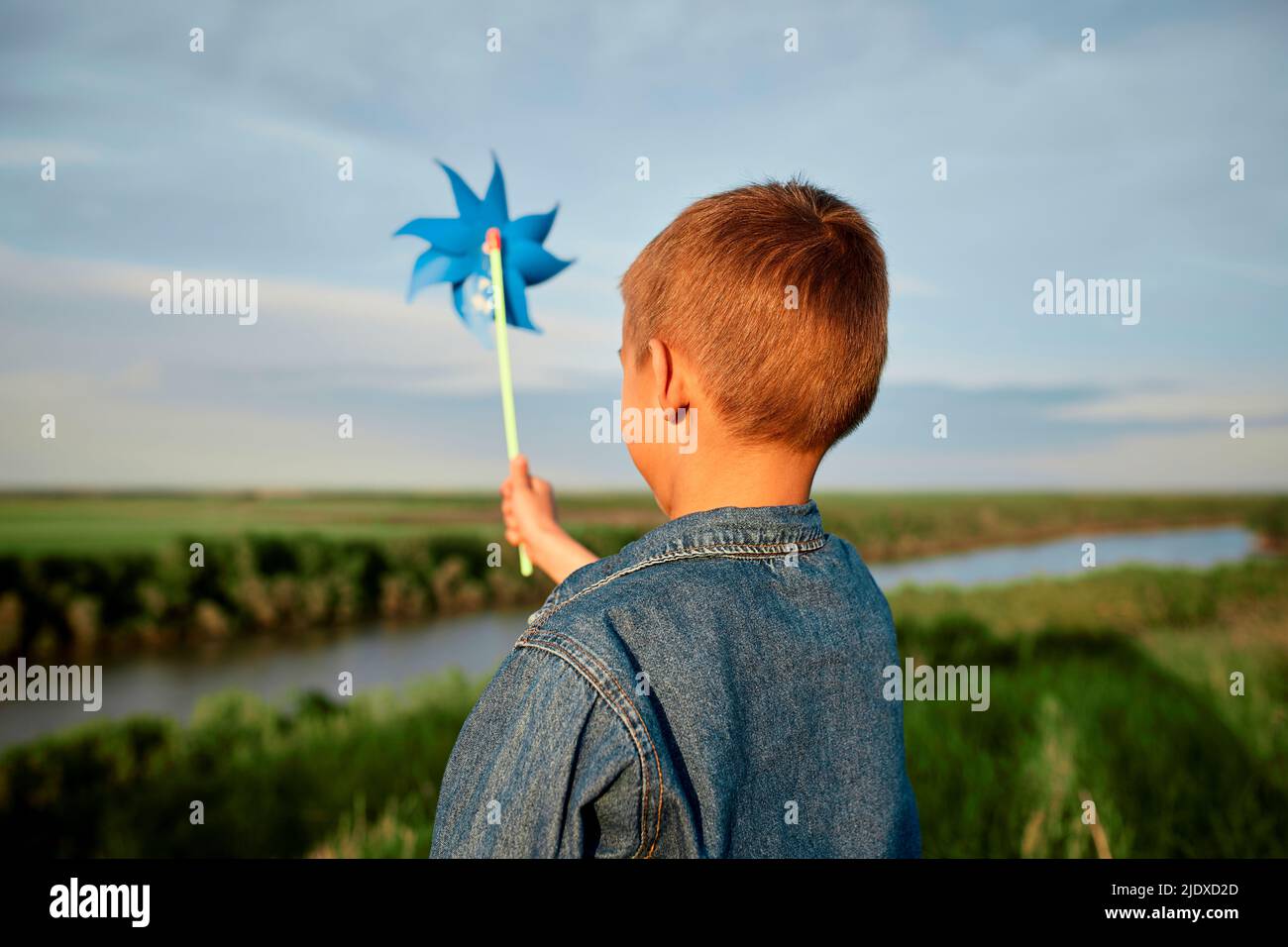 Boy holding pinwheel toy by river in agricultural field Stock Photo - Alamy