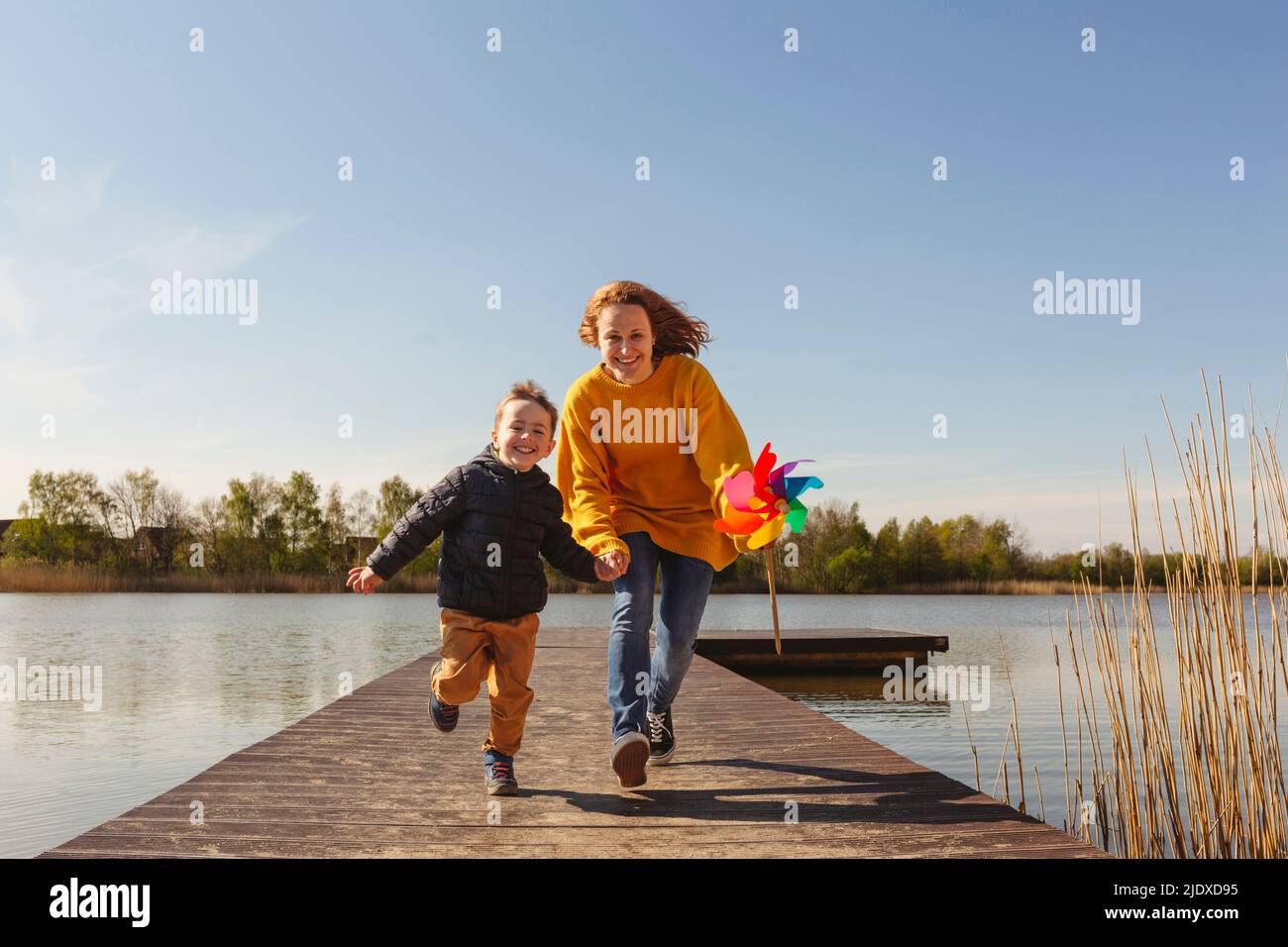 Happy woman with son running on jetty Stock Photo - Alamy