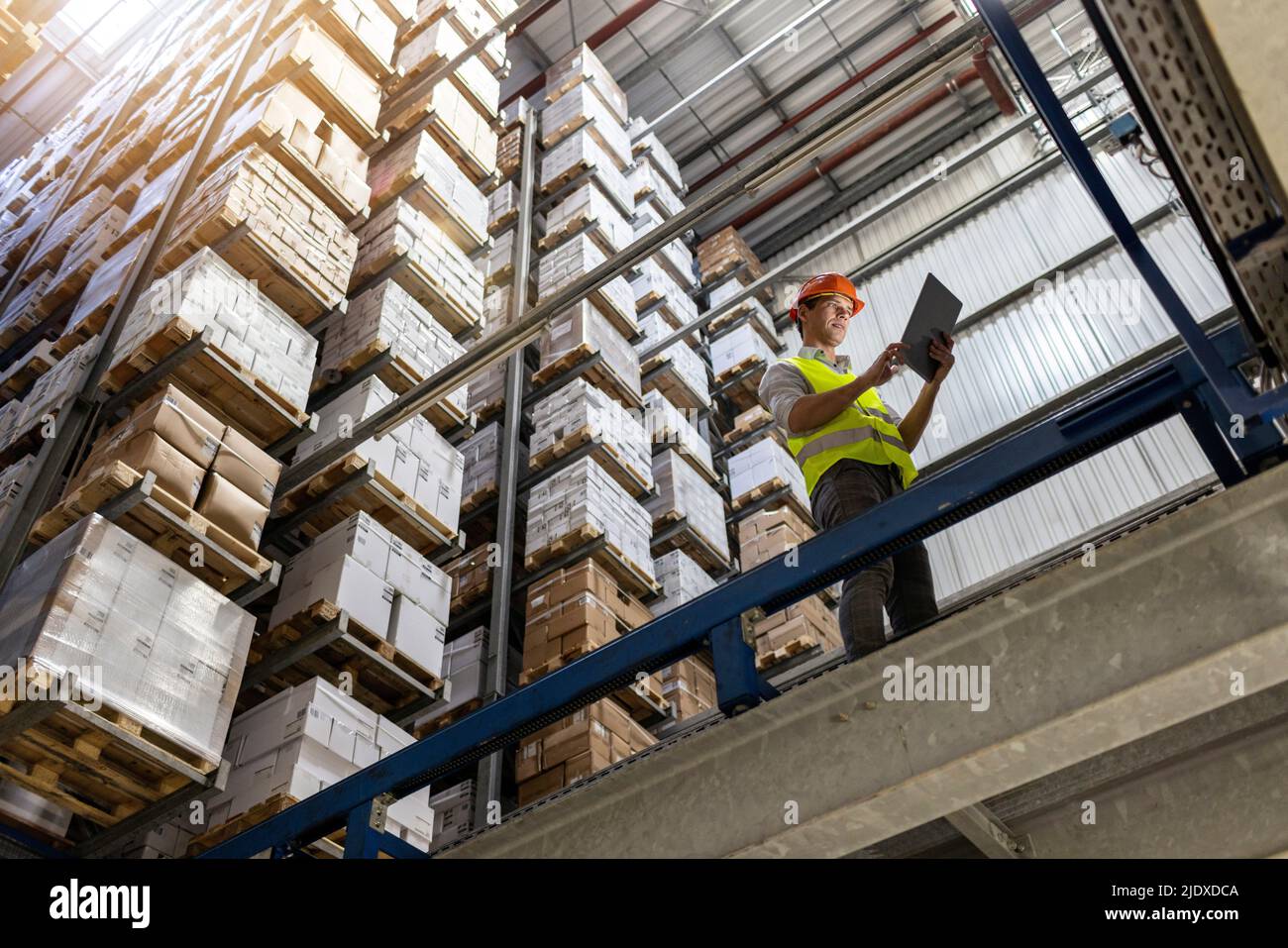 Worker using tablet PC standing by railing in warehouse Stock Photo - Alamy