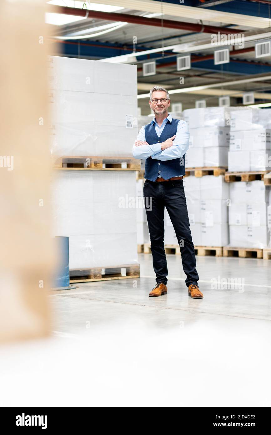 Manager standing with arms crossed in warehouse Stock Photo - Alamy