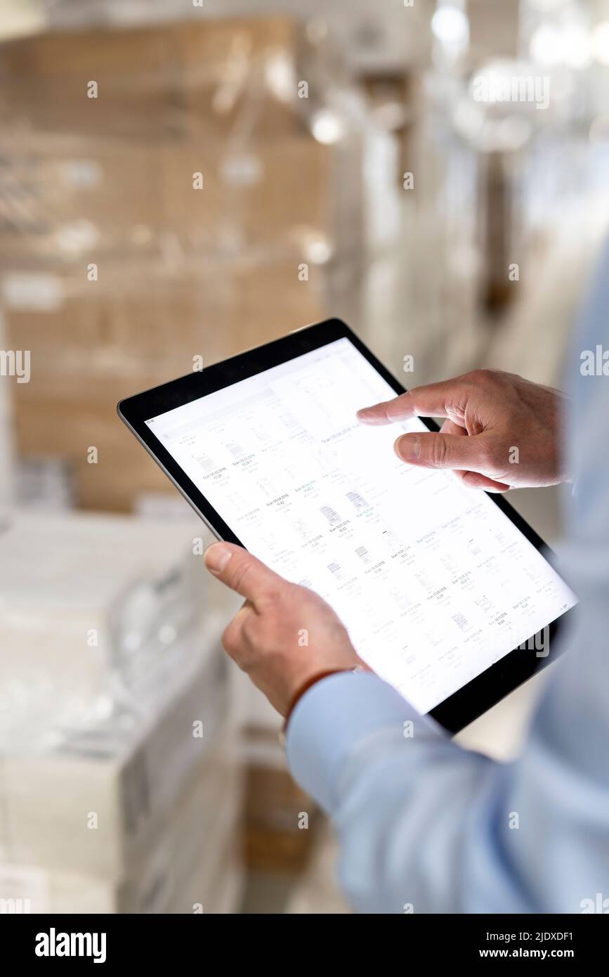 Hands of manager checking inventory through tablet PC in warehouse ...