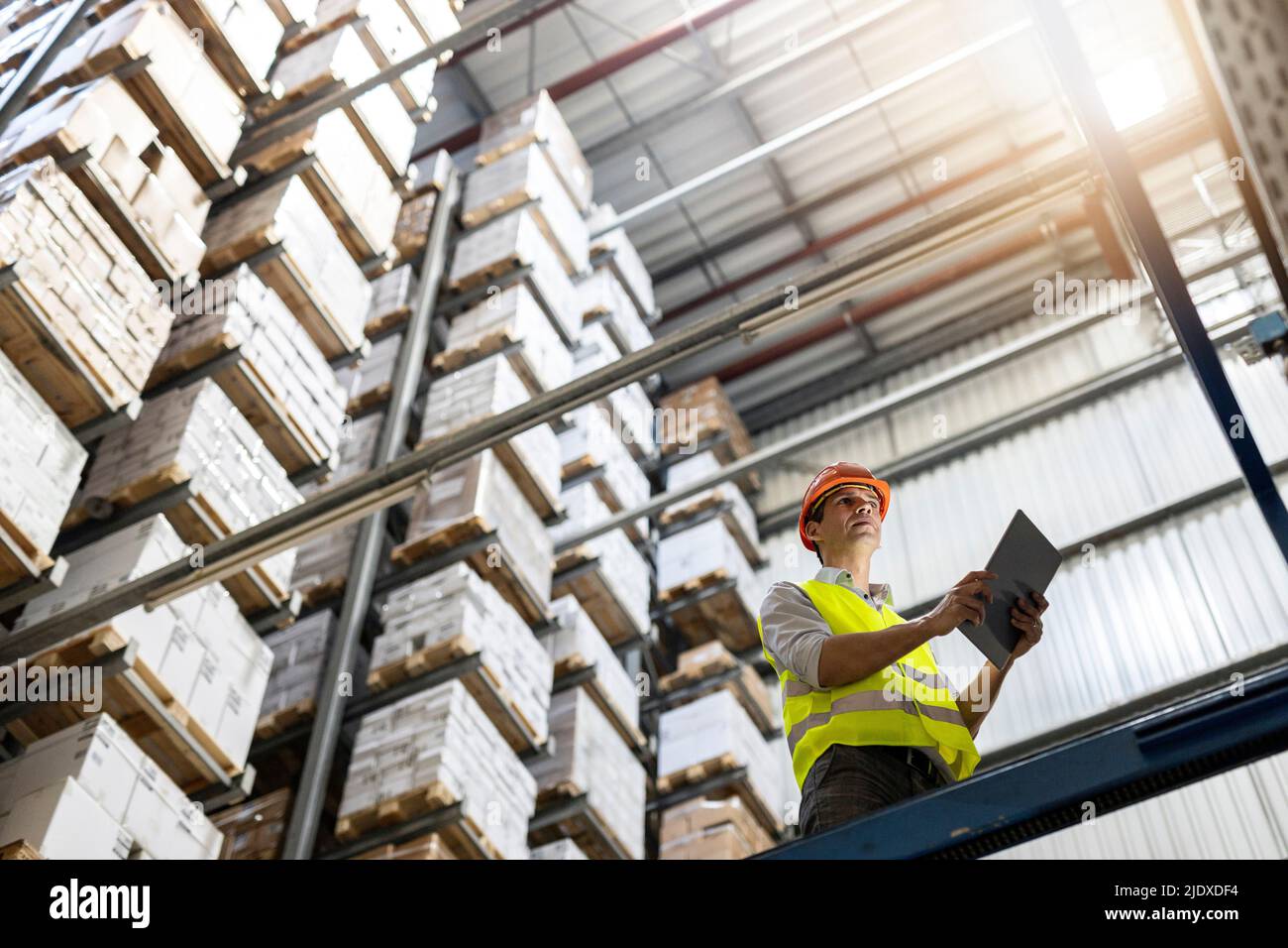 Worker with tablet PC checking inventory standing by railing in ...