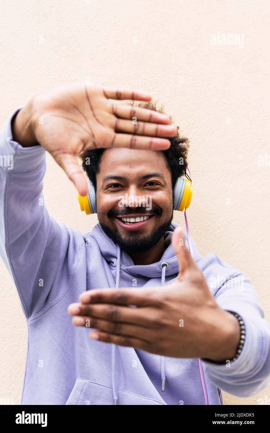 Happy man making finger frame in front of cream colored wall Stock ...