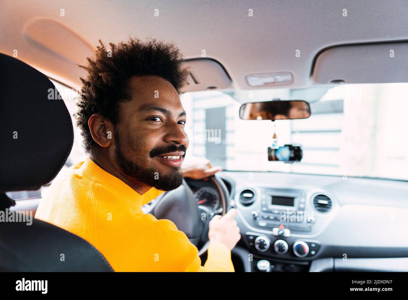 Smiling Afro man driving car looking over shoulder Stock Photo - Alamy