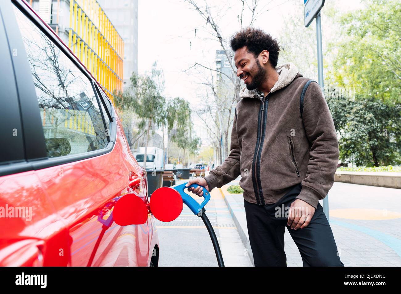 Happy man charging electric car at station Stock Photo - Alamy
