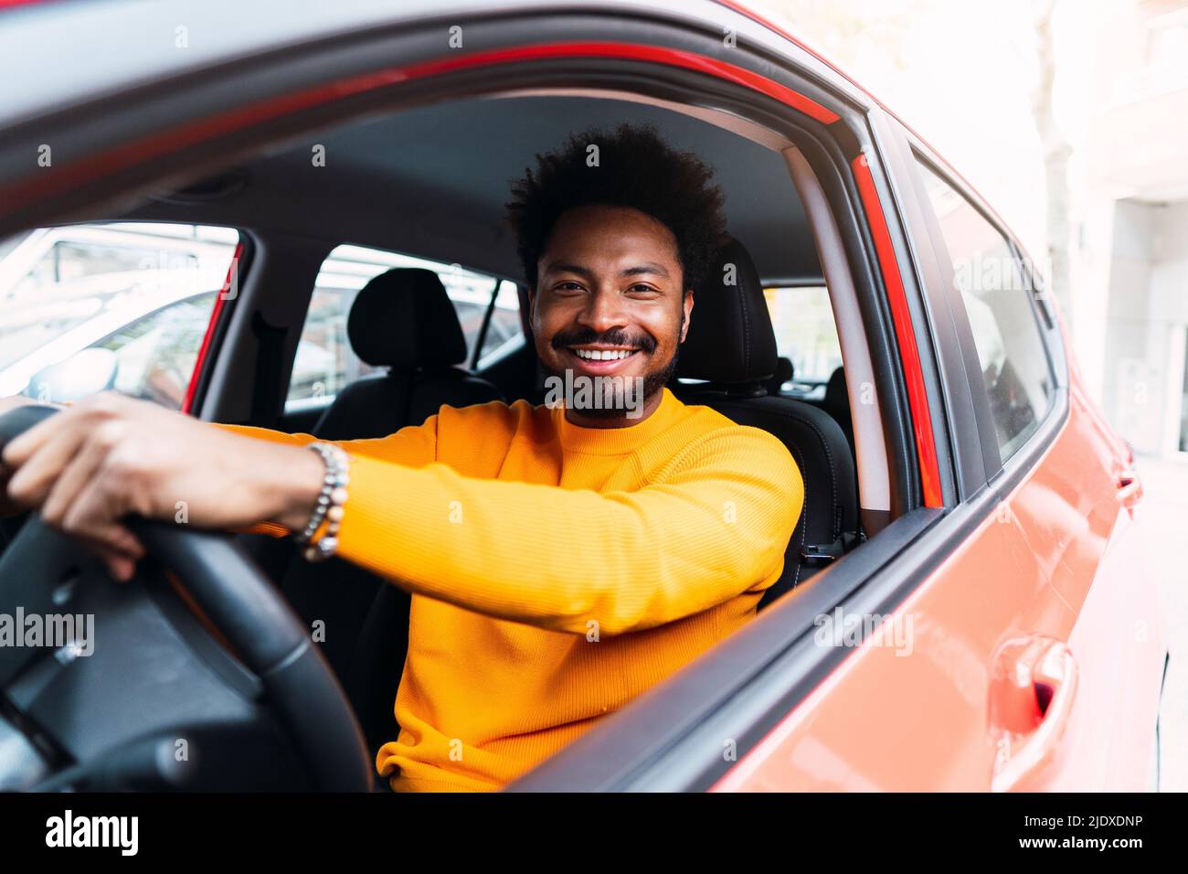 Smiling Afro man sitting on driver's seat Stock Photo - Alamy