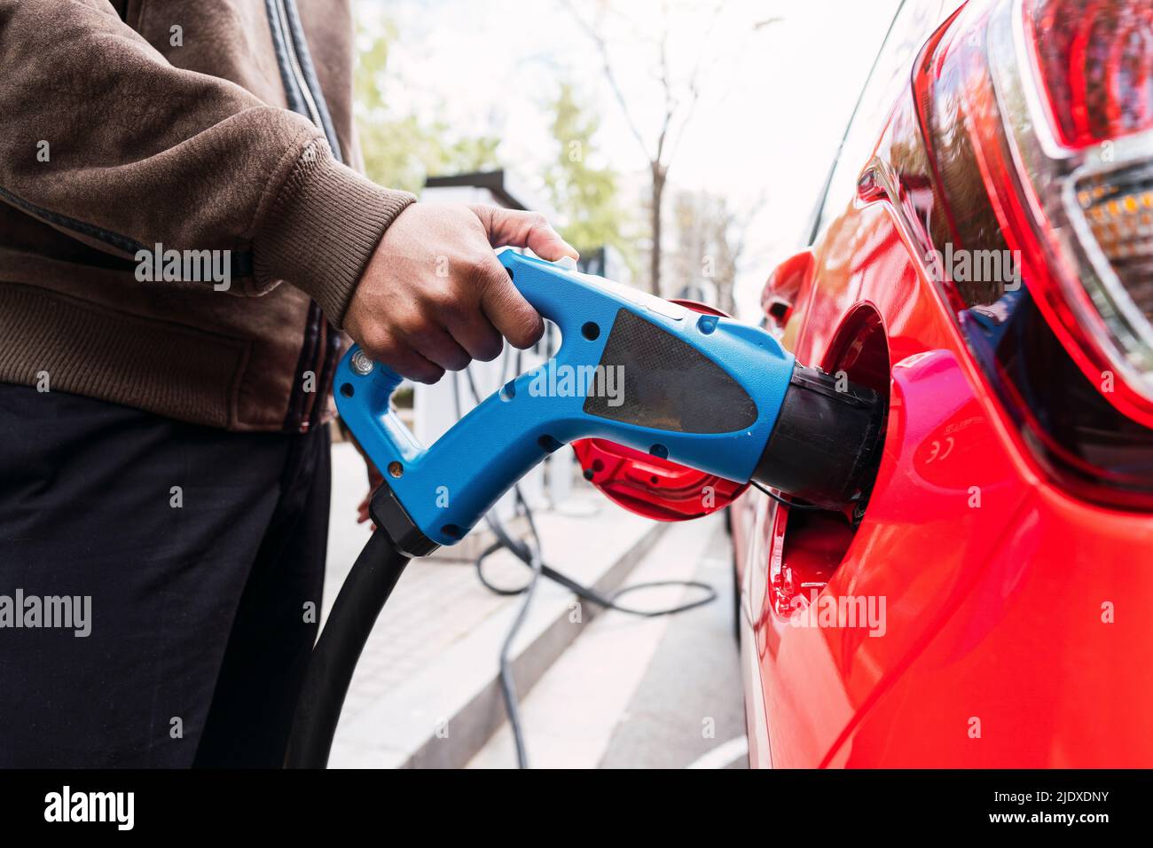 Hand of man charging red electric car Stock Photo - Alamy