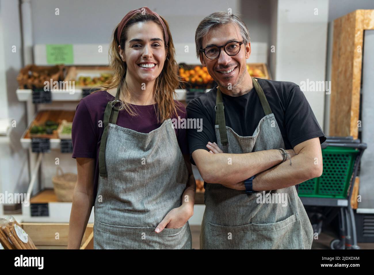 Smiling store owners wearing aprons standing in organic market Stock ...
