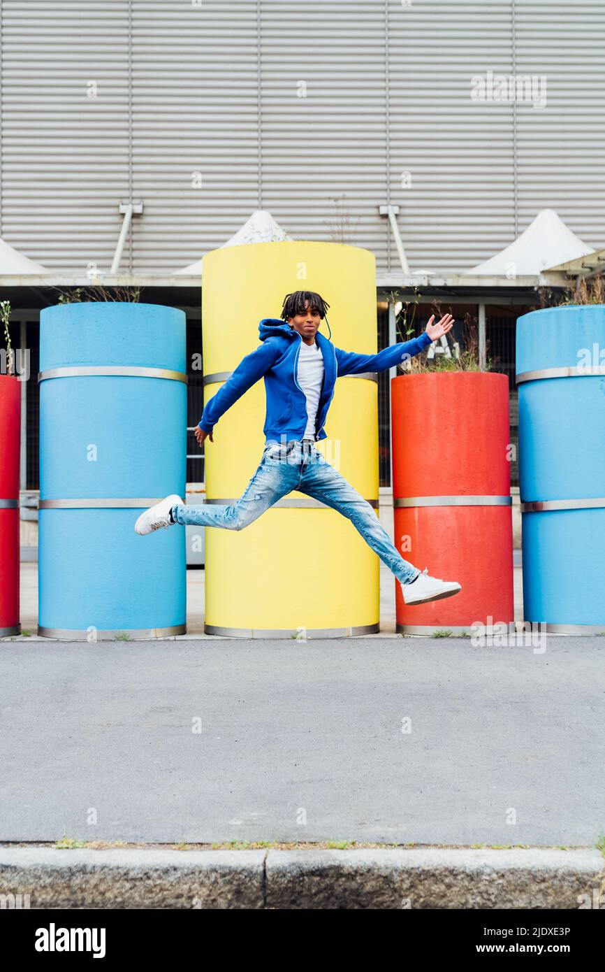 Happy young man jumping in front of concrete pipes Stock Photo - Alamy