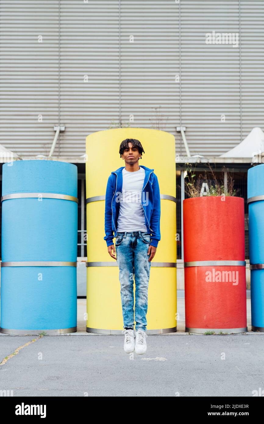 Young man jumping in front of concrete pipes Stock Photo - Alamy