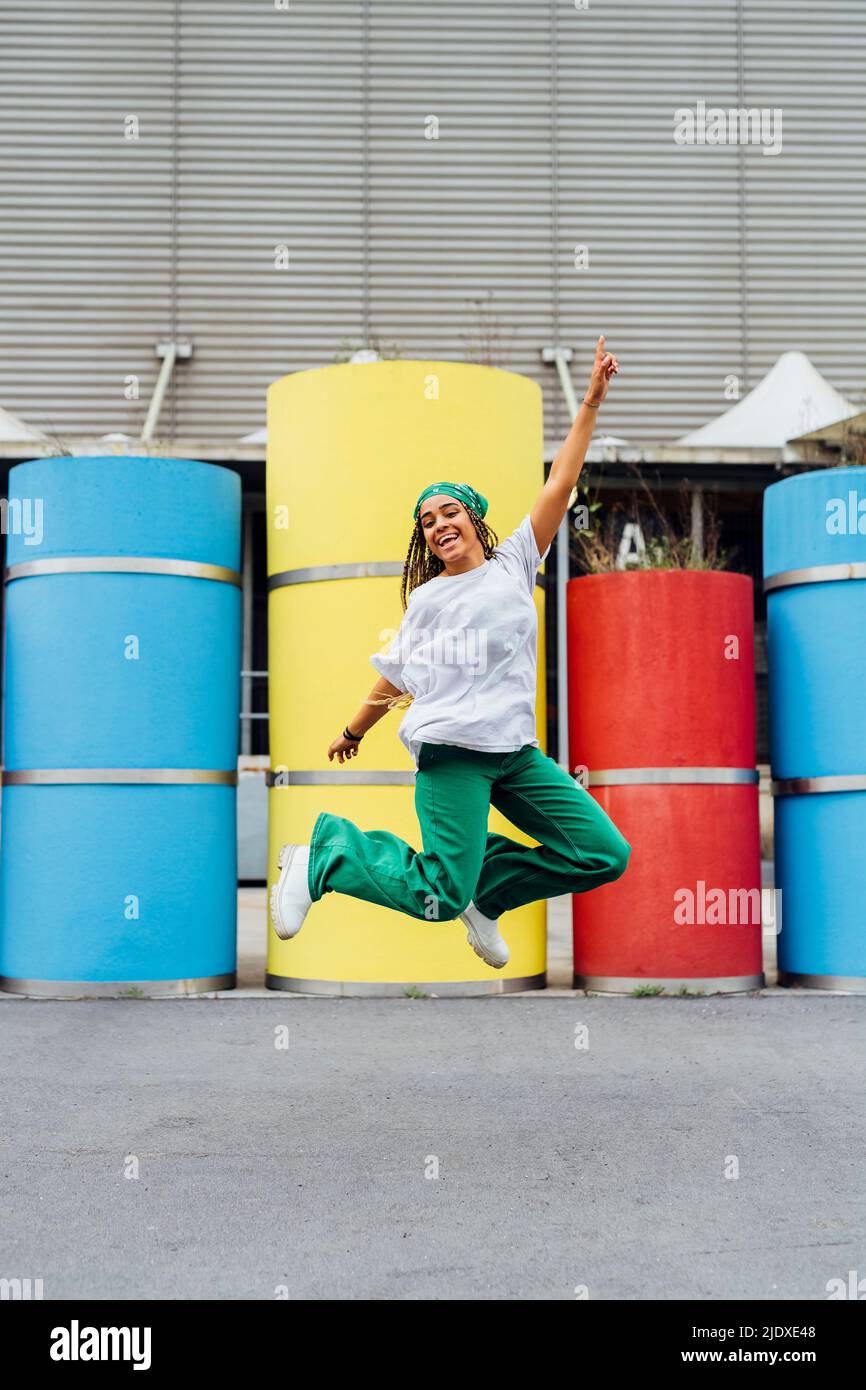 Happy young woman jumping in front of concrete pipes Stock Photo - Alamy