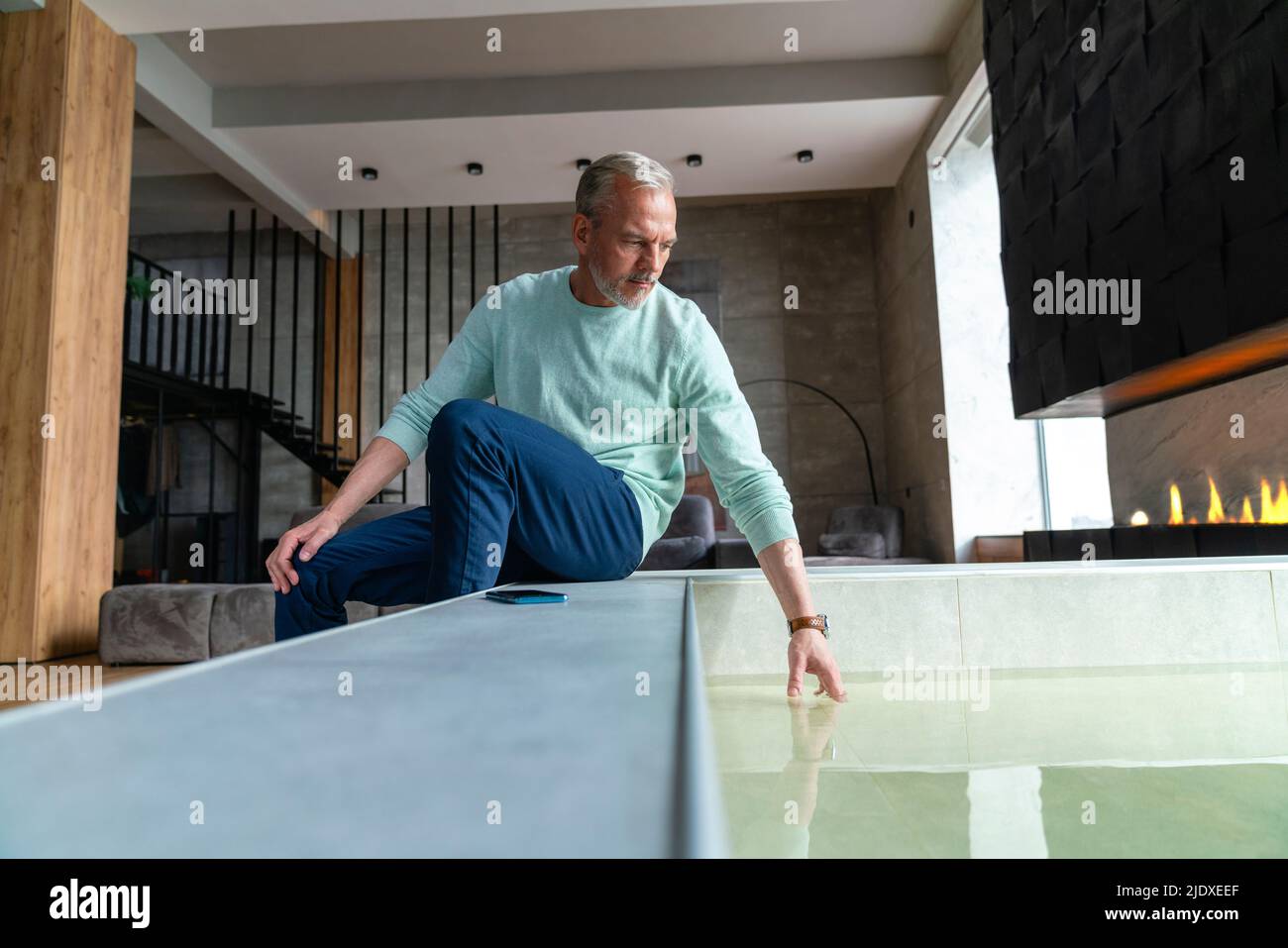 Mature man dipping hand in bathtub at home Stock Photo - Alamy