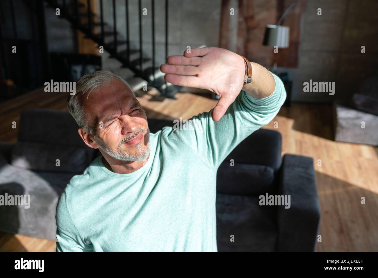 Man shielding eyes from sunlight with hand at home Stock Photo - Alamy