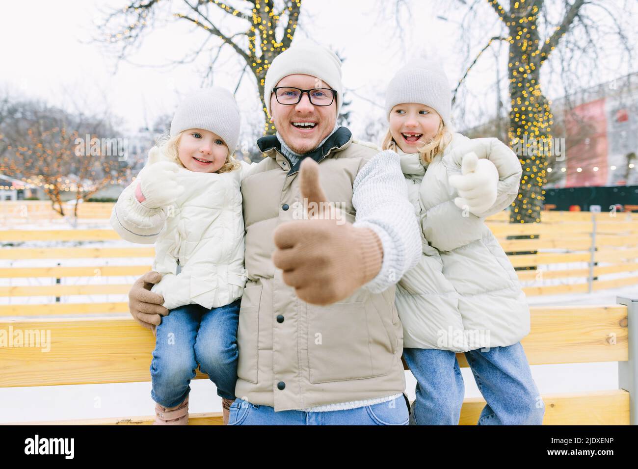 Happy father and daughters gesturing thumbs up at Christmas market ...