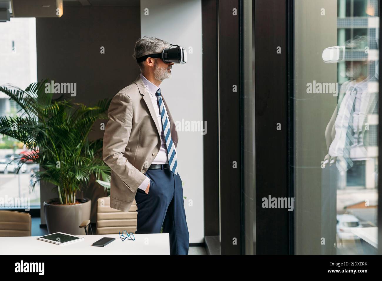 Businessman wearing virtual reality simulator standing with hands in ...