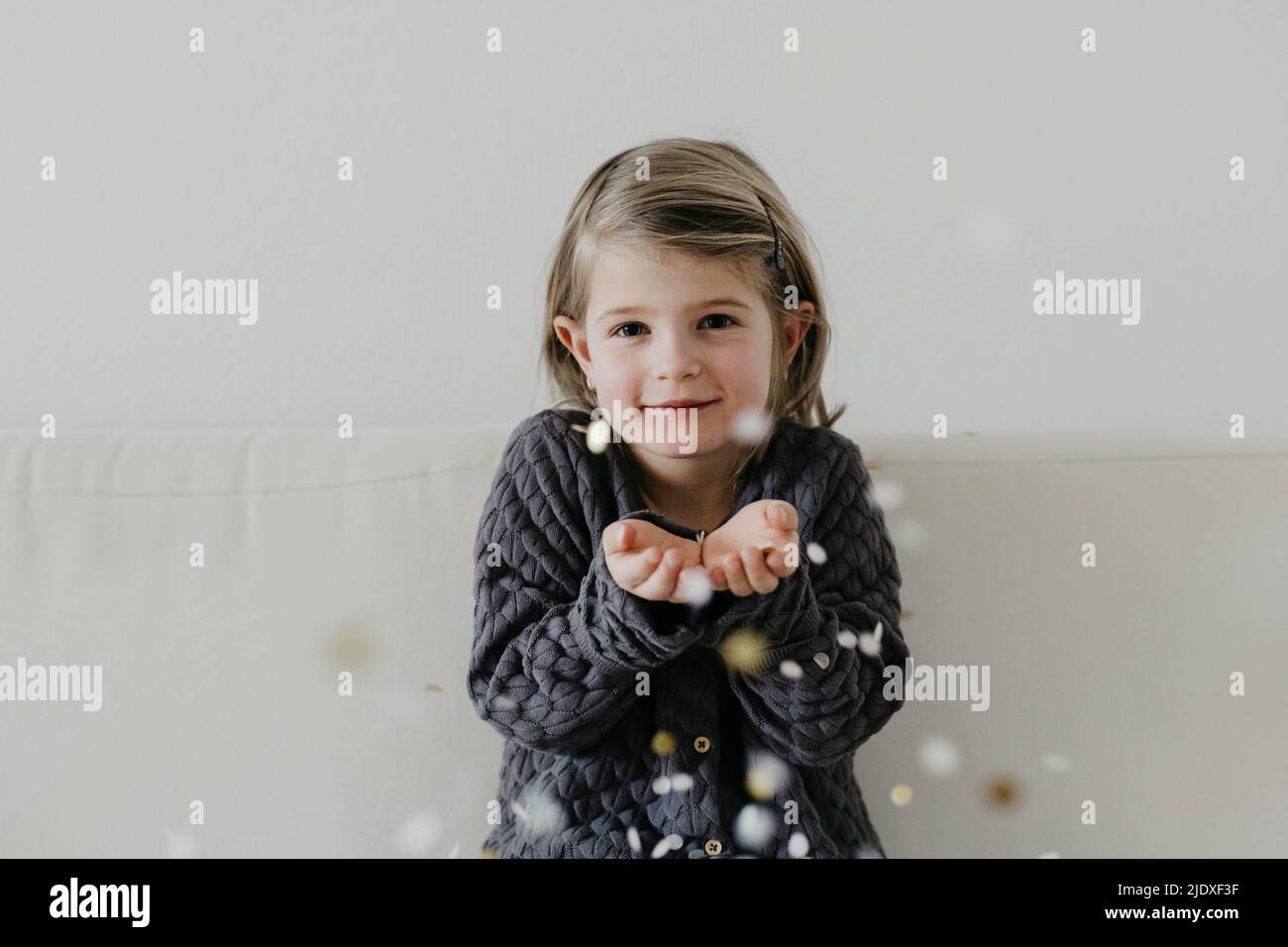 Cute girl with hands cupped playing with confetti Stock Photo - Alamy