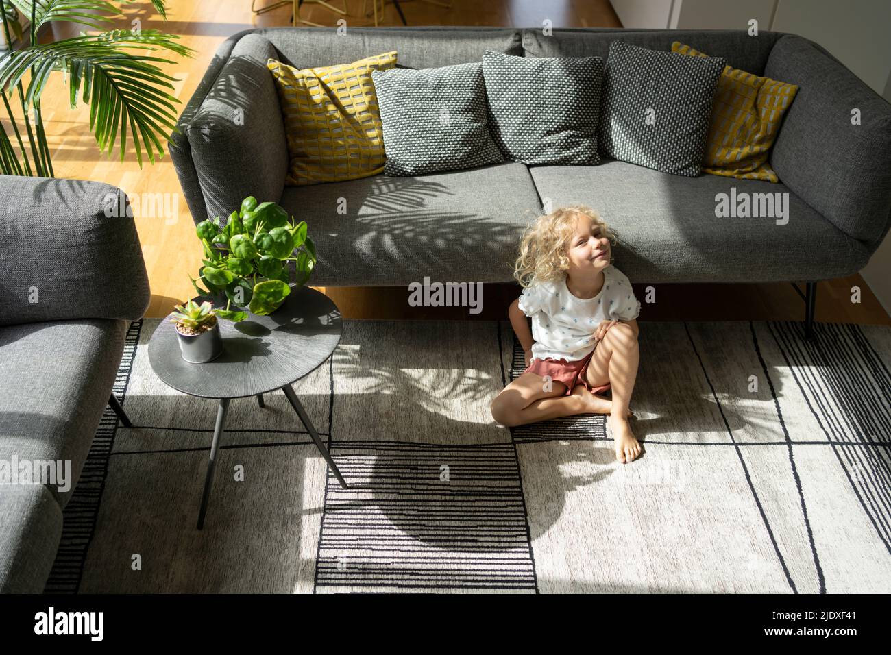 Girl sitting on carpet in living room at home Stock Photo - Alamy