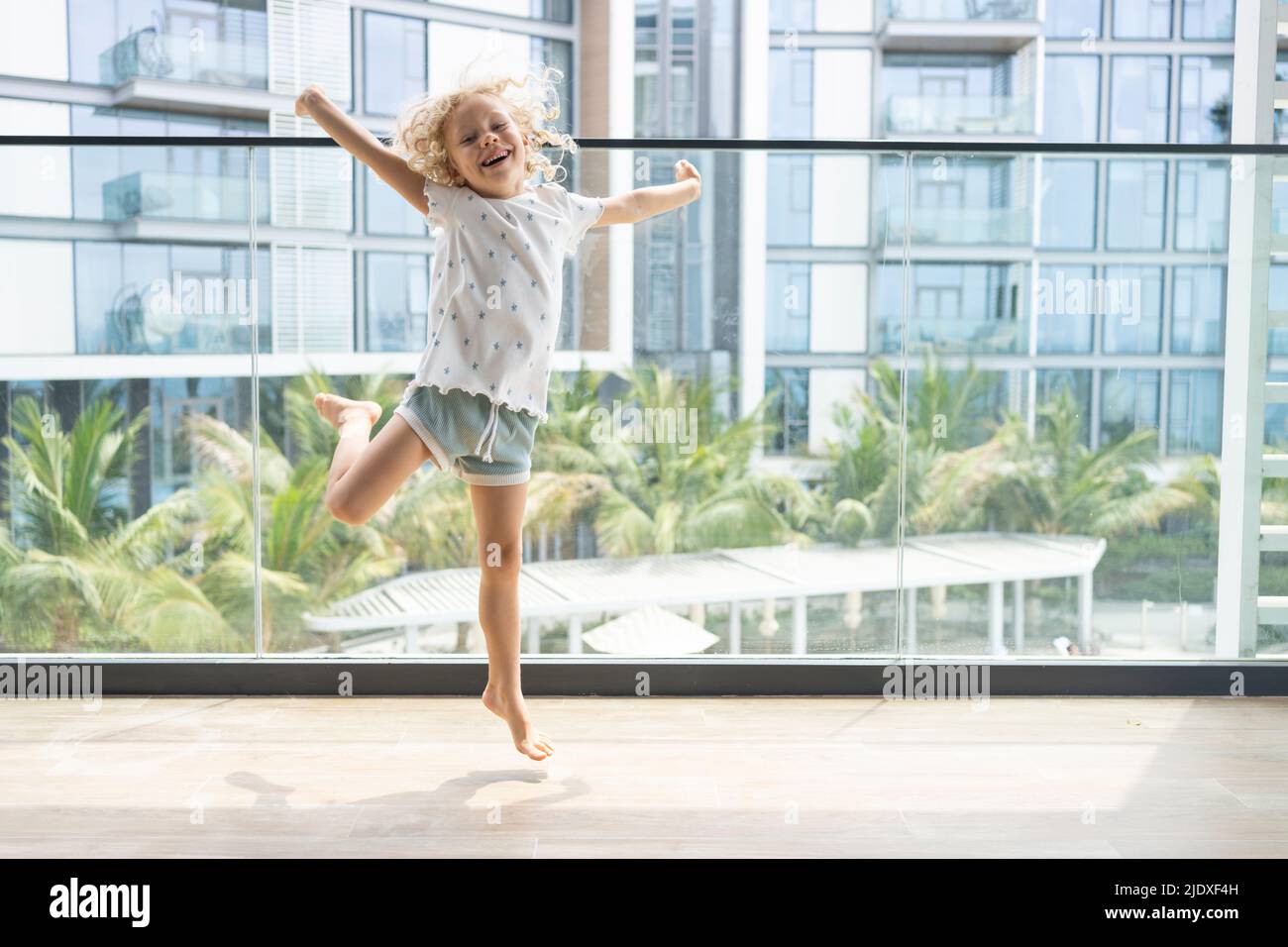 Cheerful girl jumping on balcony Stock Photo - Alamy