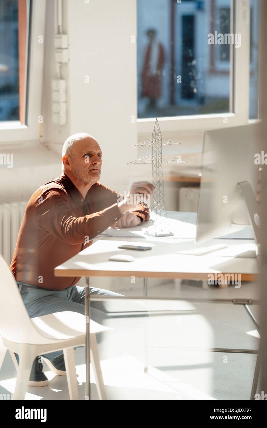 Engineer analyzing electricity pylon model at desk in office Stock ...