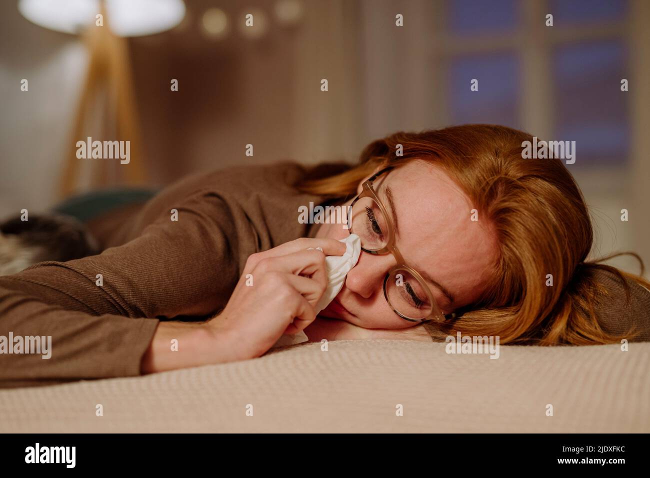 Sad redhead woman with tissue paper crying on bed at home Stock Photo ...