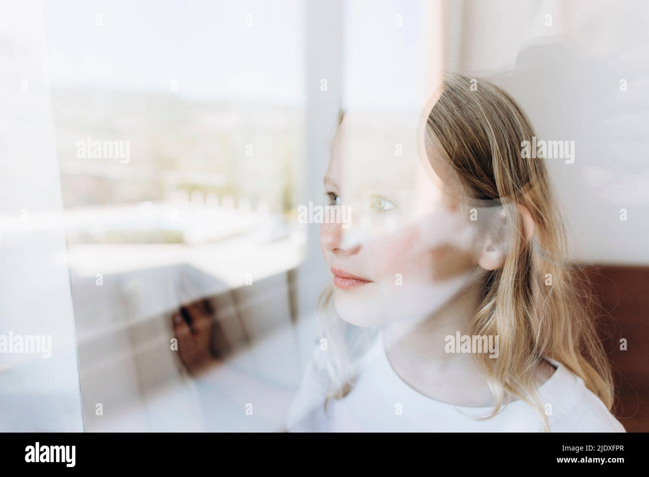 Contemplative girl looking through window Stock Photo - Alamy