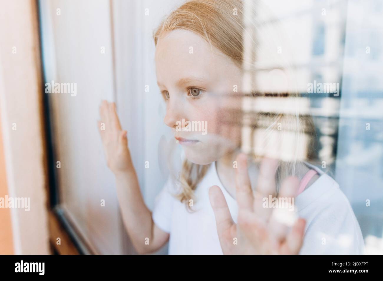 Thoughtful girl looking through glass window Stock Photo - Alamy