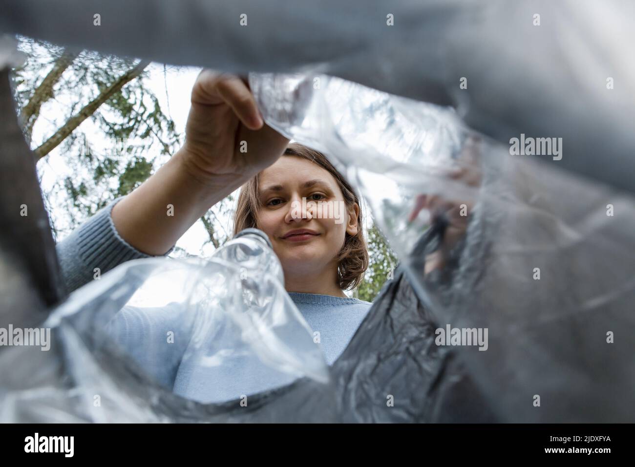 Woman putting plastic bottles in garbage bag Stock Photo - Alamy