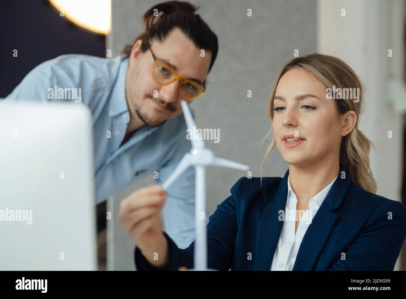 Engineer discussing with colleague over wind turbine model in office ...