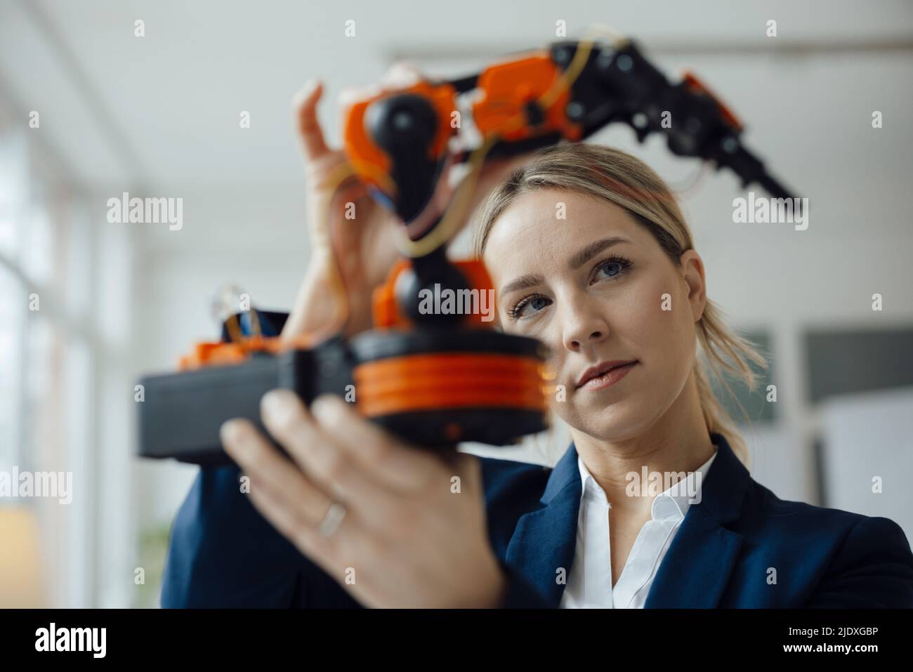 Businesswoman analyzing robotic arm model in office Stock Photo - Alamy